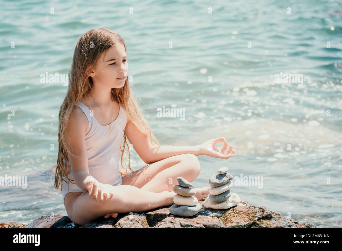 Woman with daughter bilds stones pyramid on seashore on a sunny day on ...