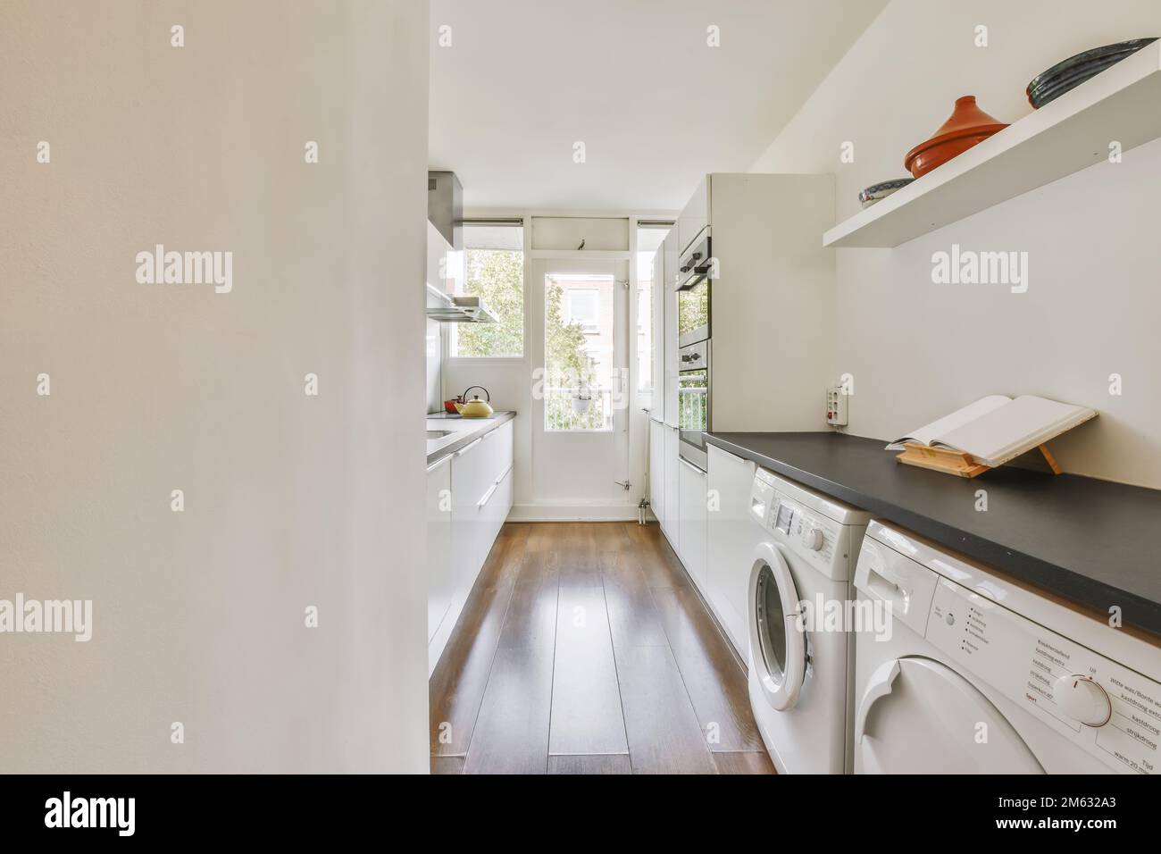 a laundry room with wood flooring and white washer in the area is well ...