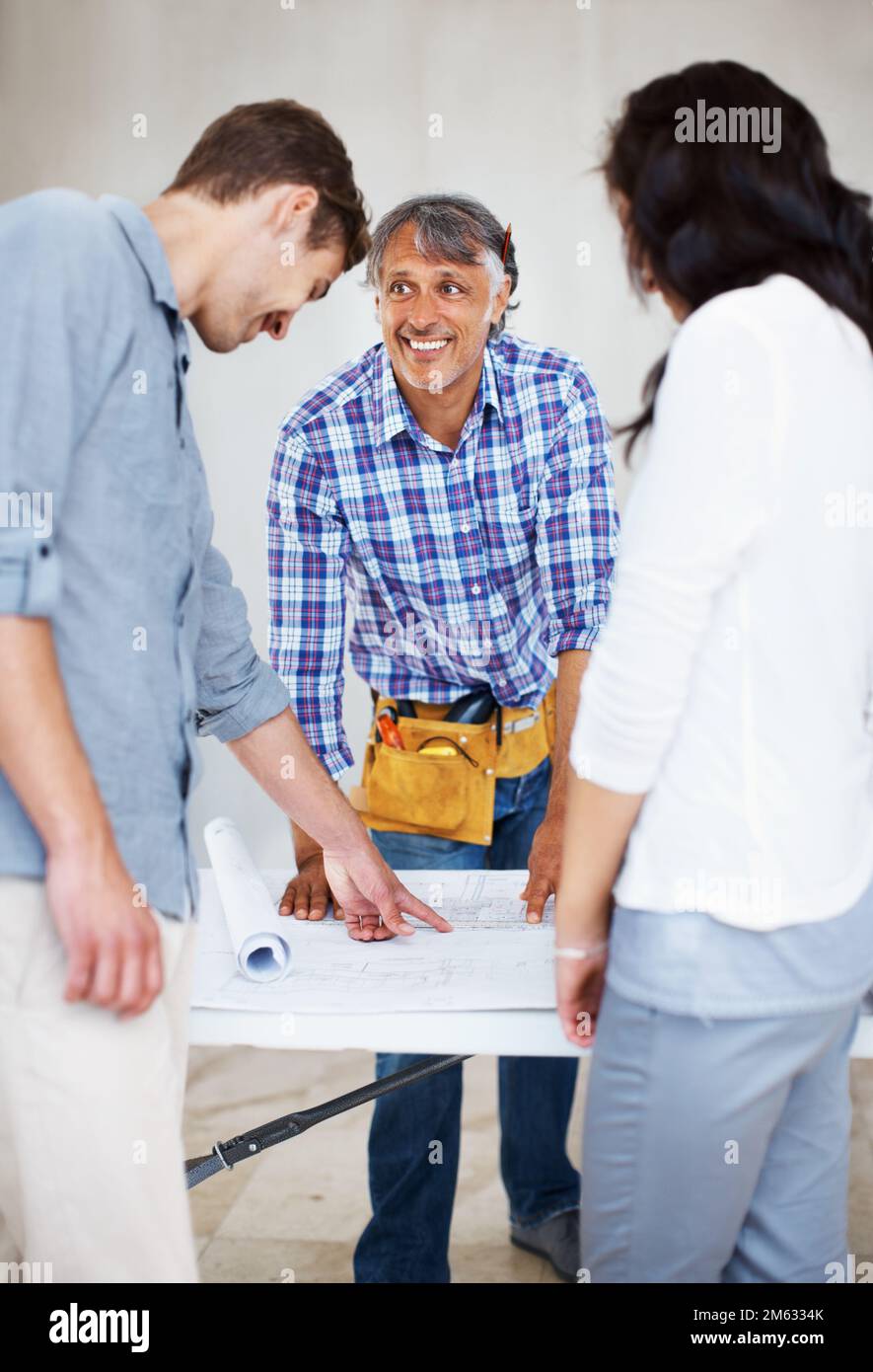 Young couple reviewing blueprint with male contractor. Young couple ...