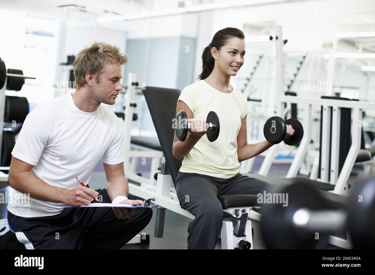 Monitoring her progress. an attractive young woman weight training with ...