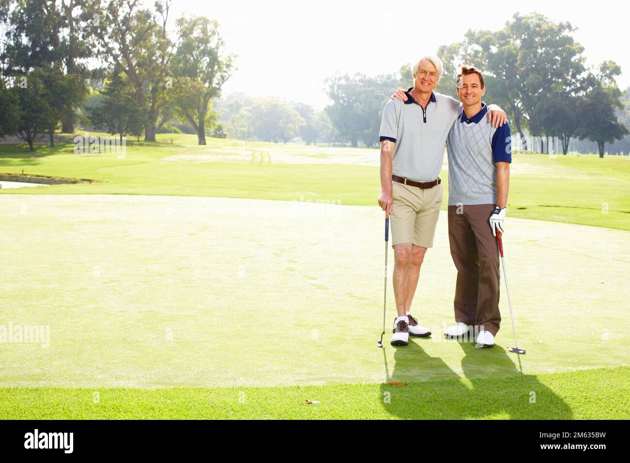 Father and son playing golf. Full length of father and son standing on ...