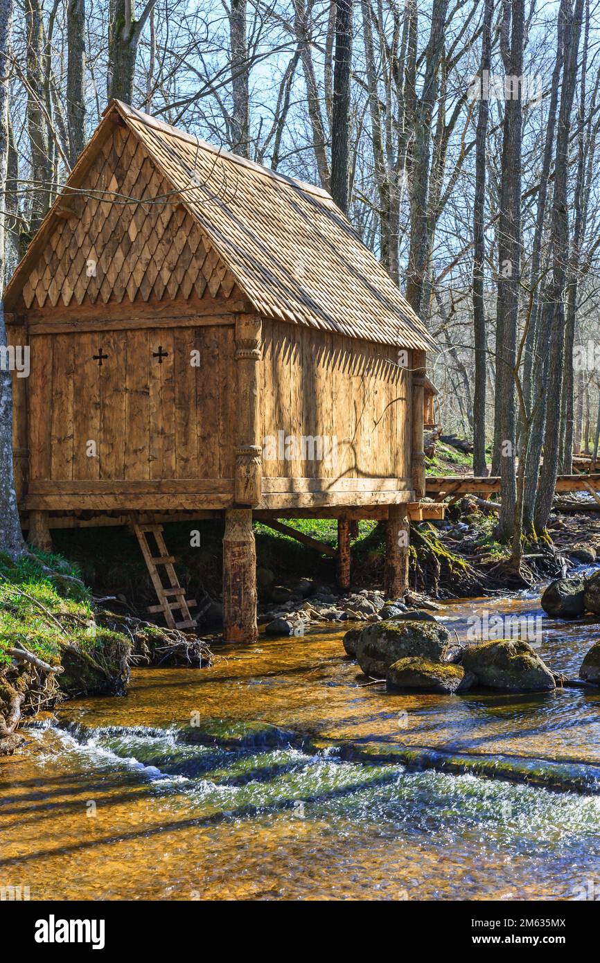 Log cabin on posts by a stream in the forest Stock Photo - Alamy