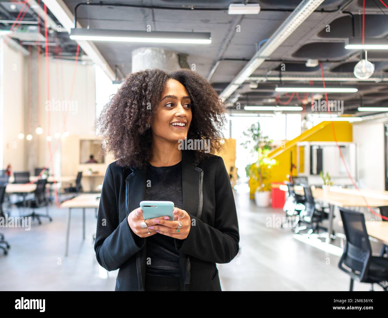 Smiling African American woman in formal wear standing in contemporary ...