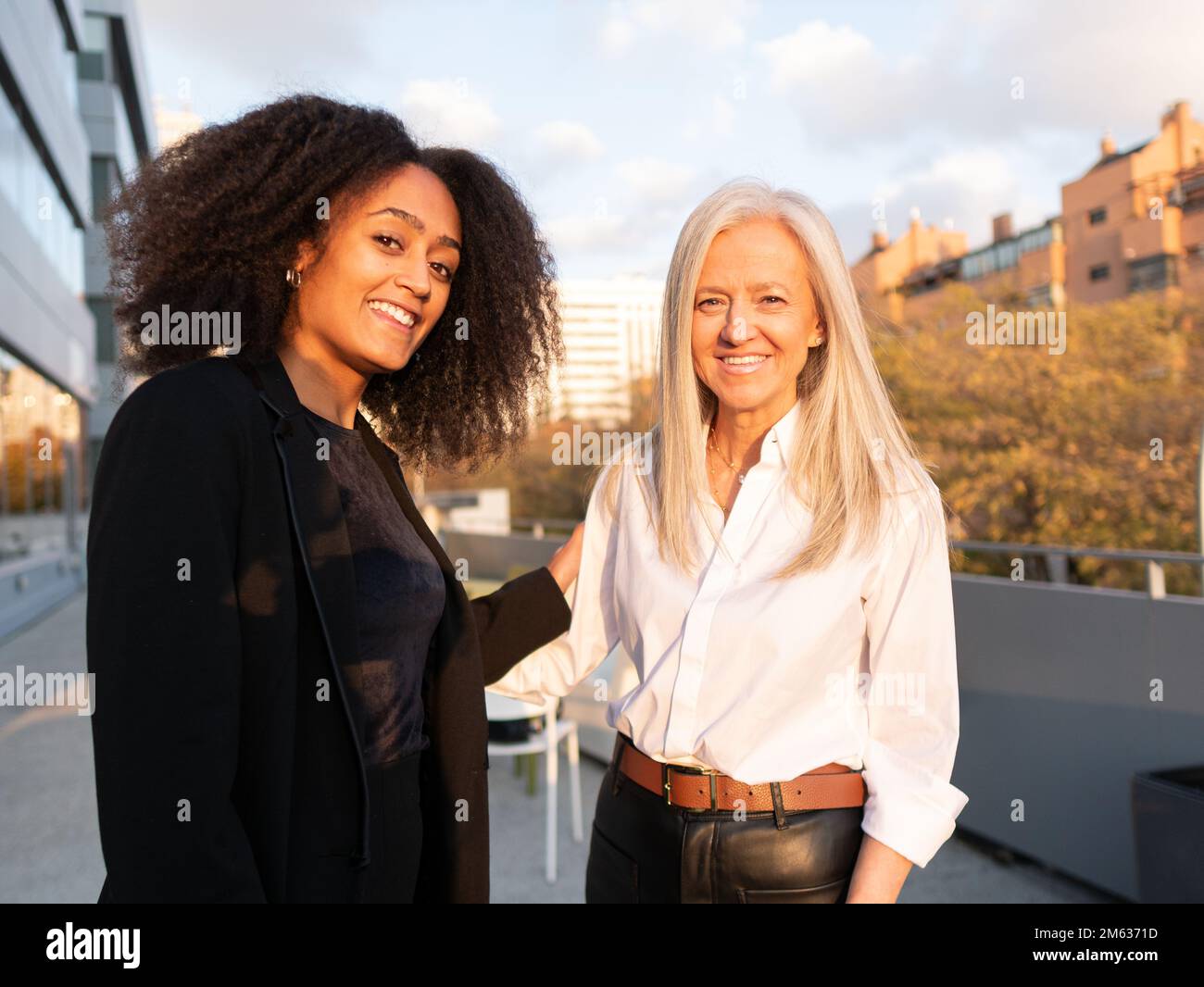 Cheerful multiracial coworkers in classy outfits smiling and looking at ...