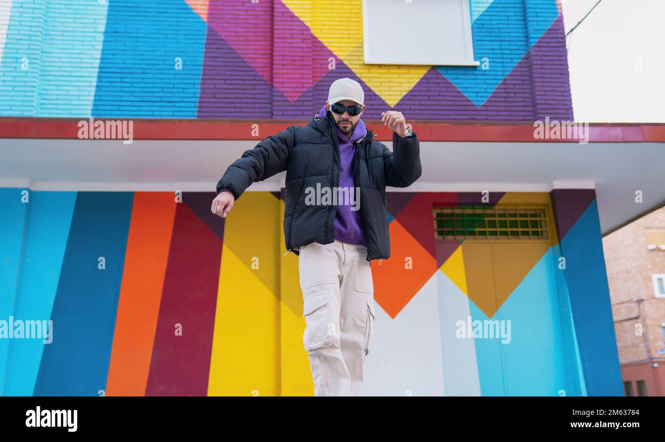 From below male dancer in stylish clothes walking on pavement near ...