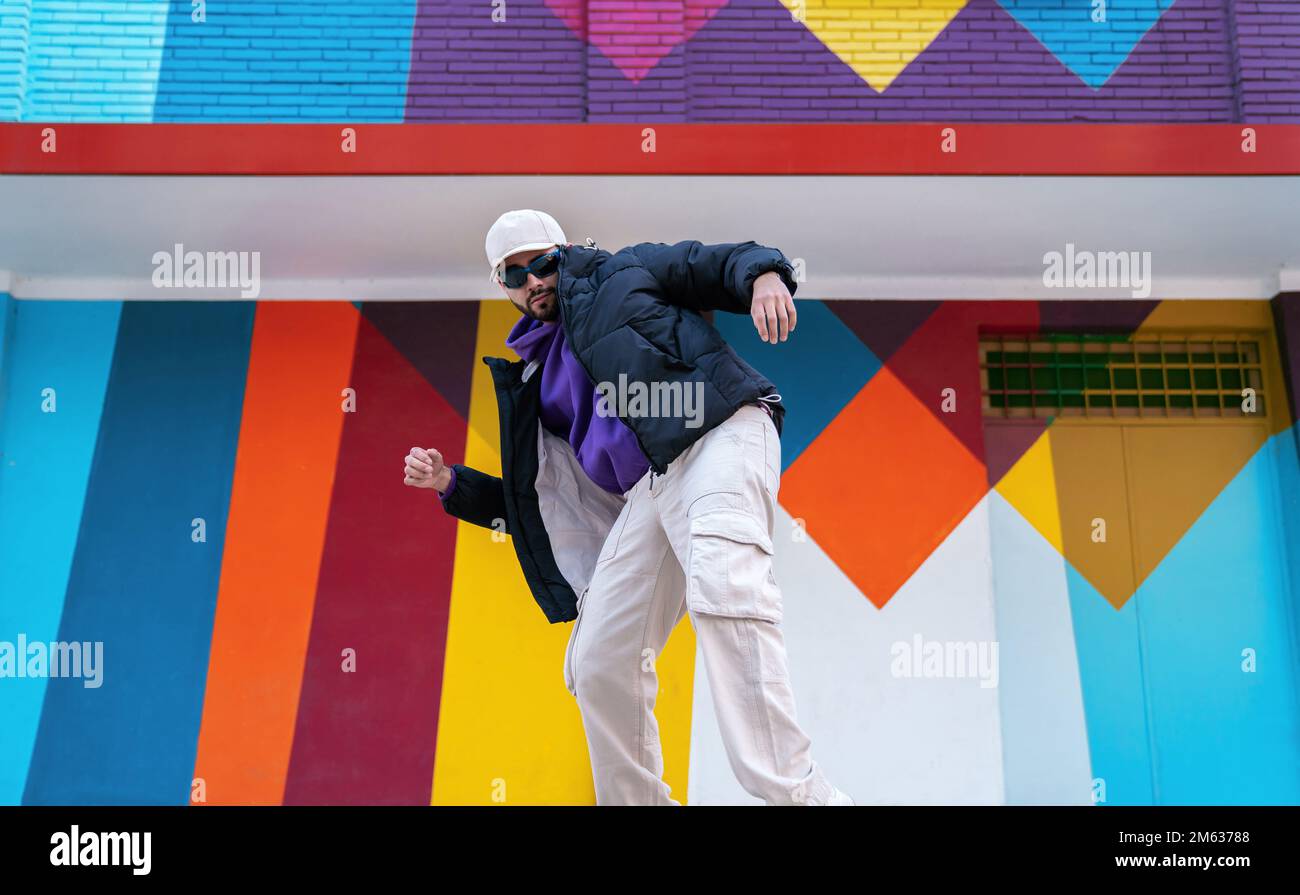 From below male dancer in stylish clothes walking on pavement near ...