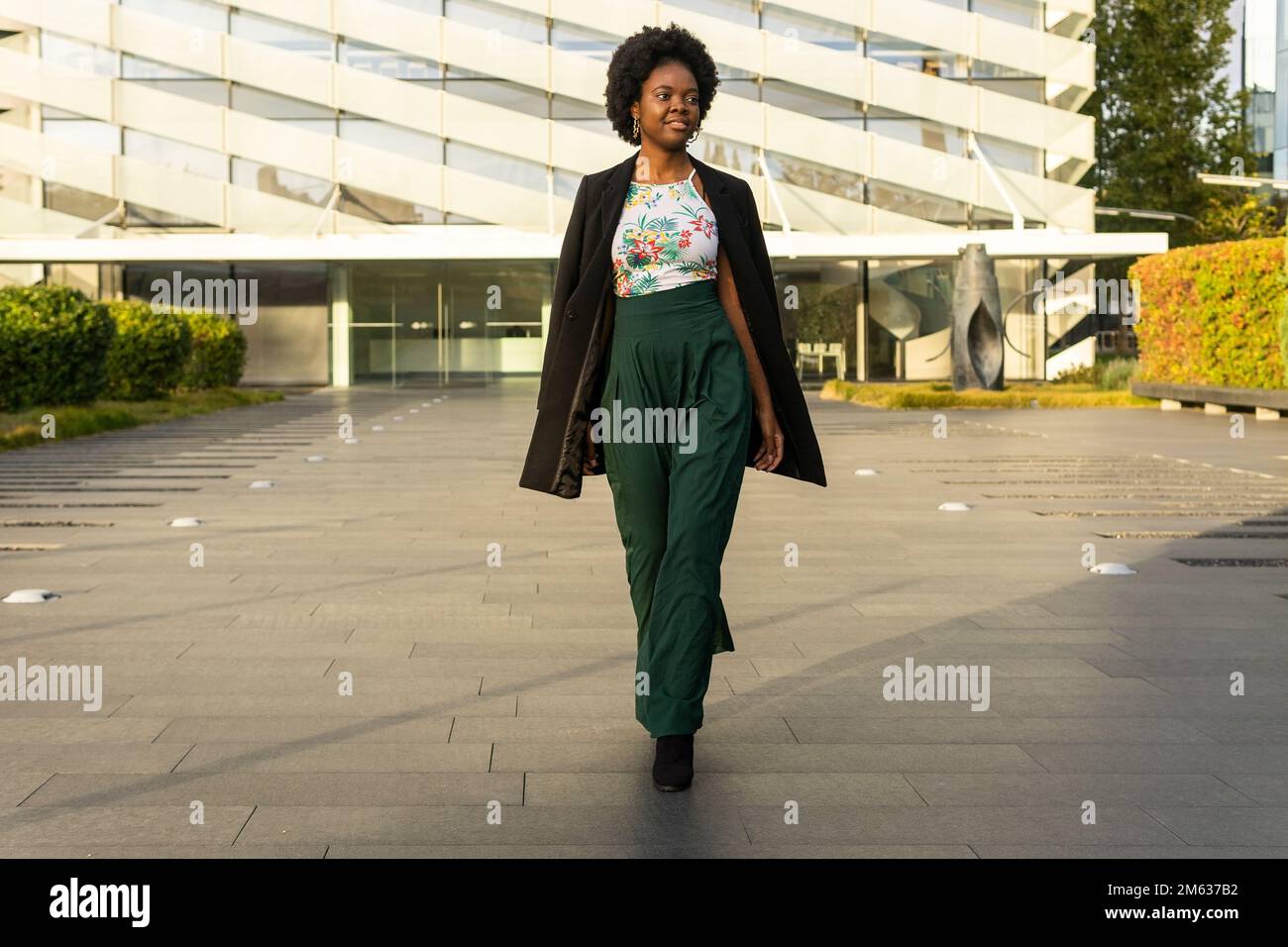 Pensive young African American female in black jacket walking near ...