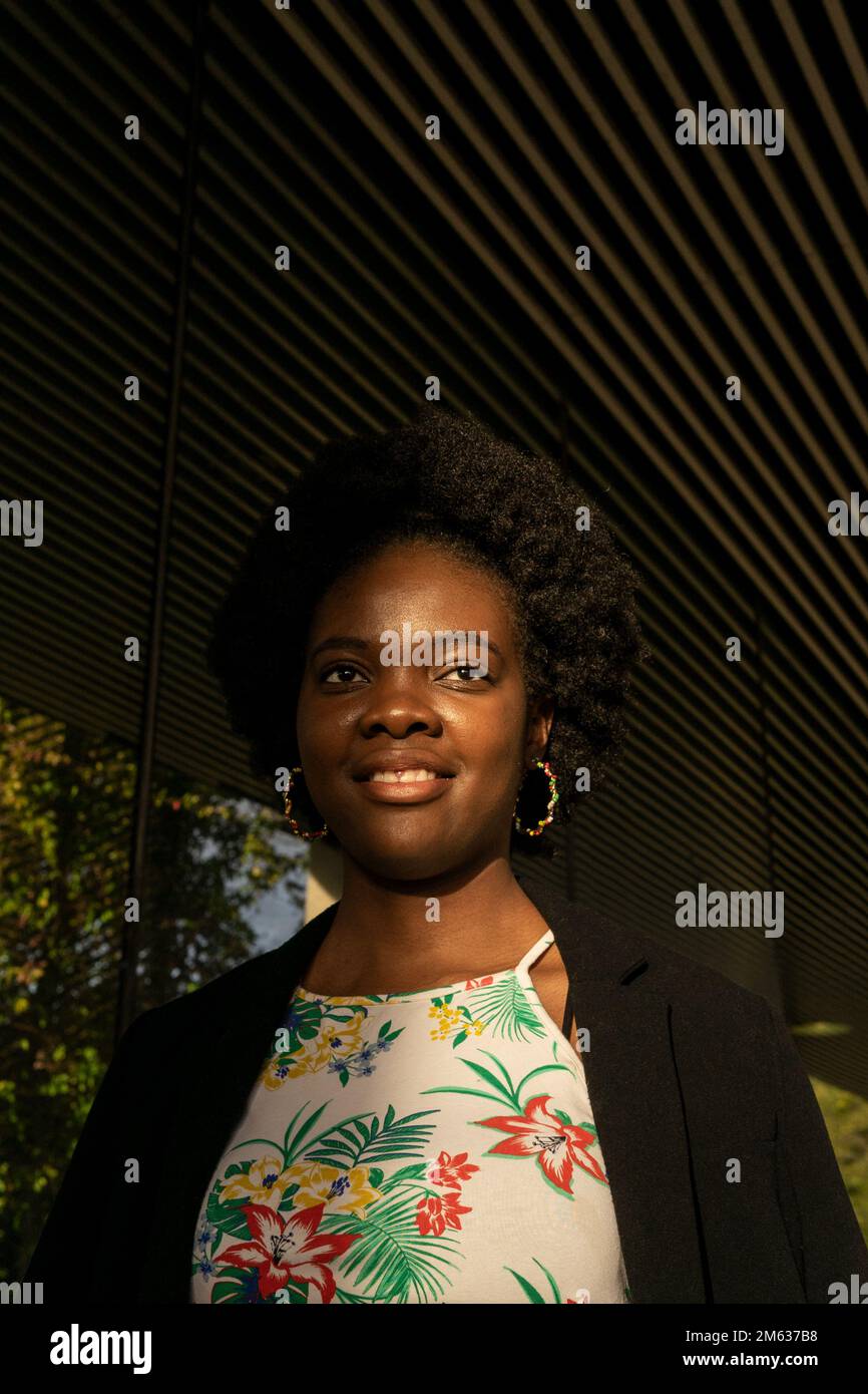 Low angle of positive young African American woman in colorful top and ...