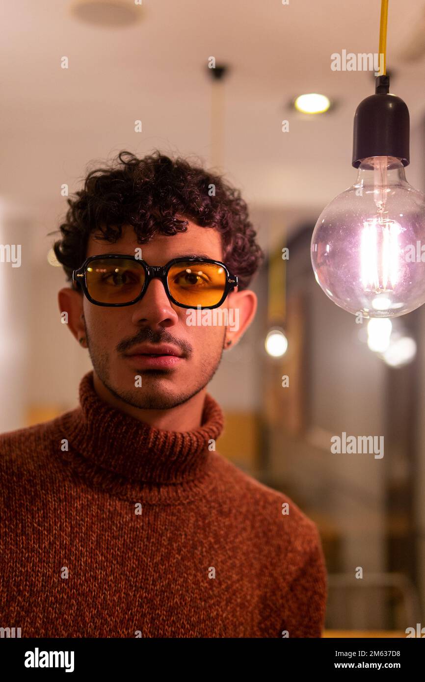 Young male in warm sweater and sunglasses standing near transparent ...