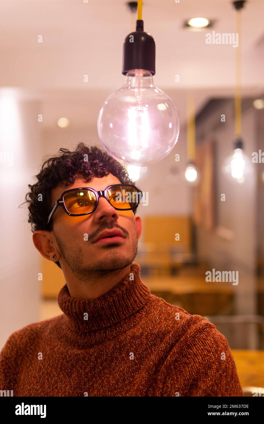 Young male in warm sweater and sunglasses standing near transparent ...