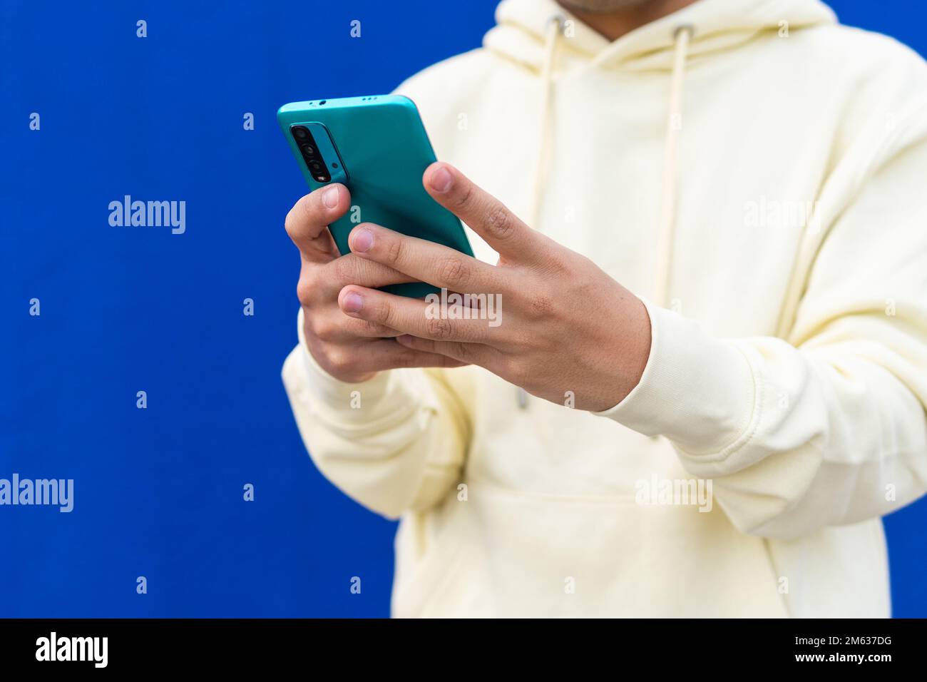From below cropped unrecognizable young male in hoodie texting on ...