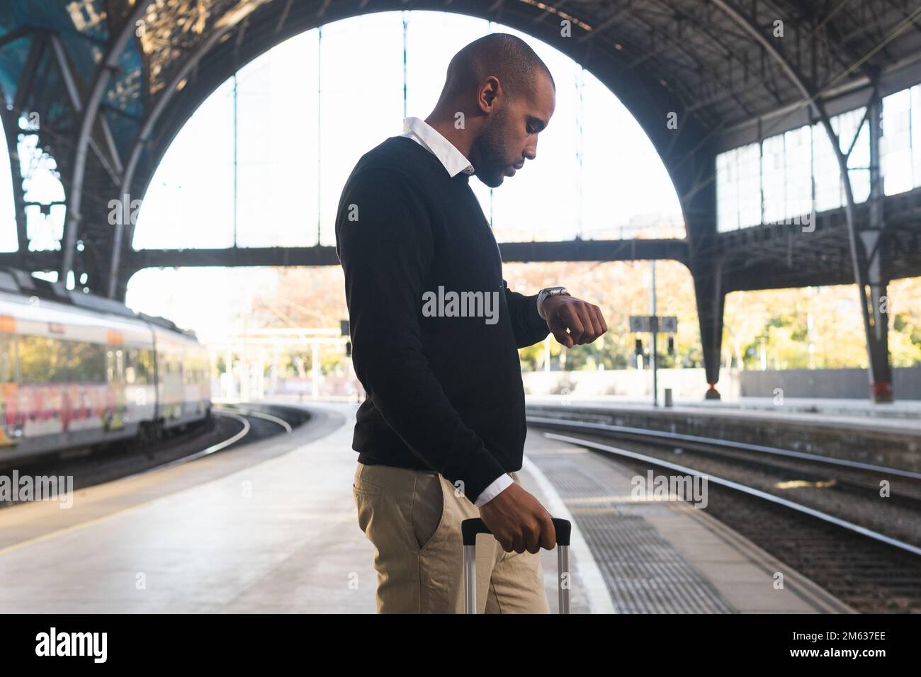 Side view of punctual ethnic man in smart casual clothes with suitcase ...