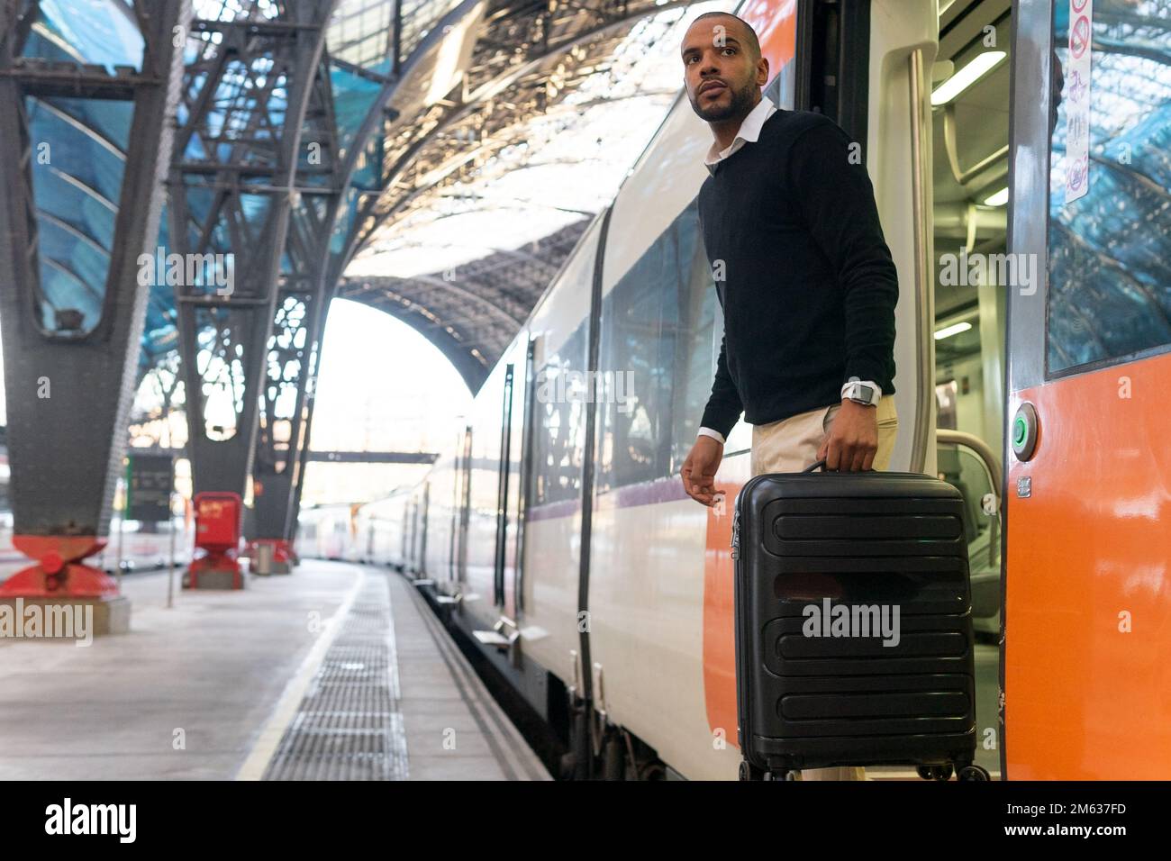 Side view of ethnic male passenger in smart casual outfit carrying ...