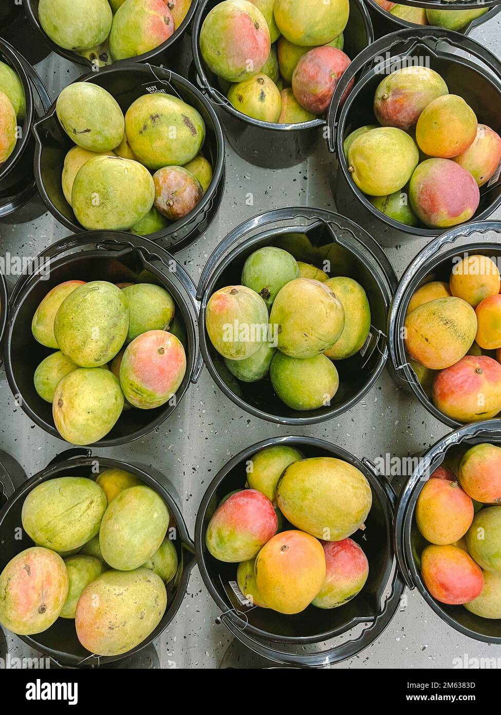 Top view of fresh juicy mangoes in black buckets placed on table in ...
