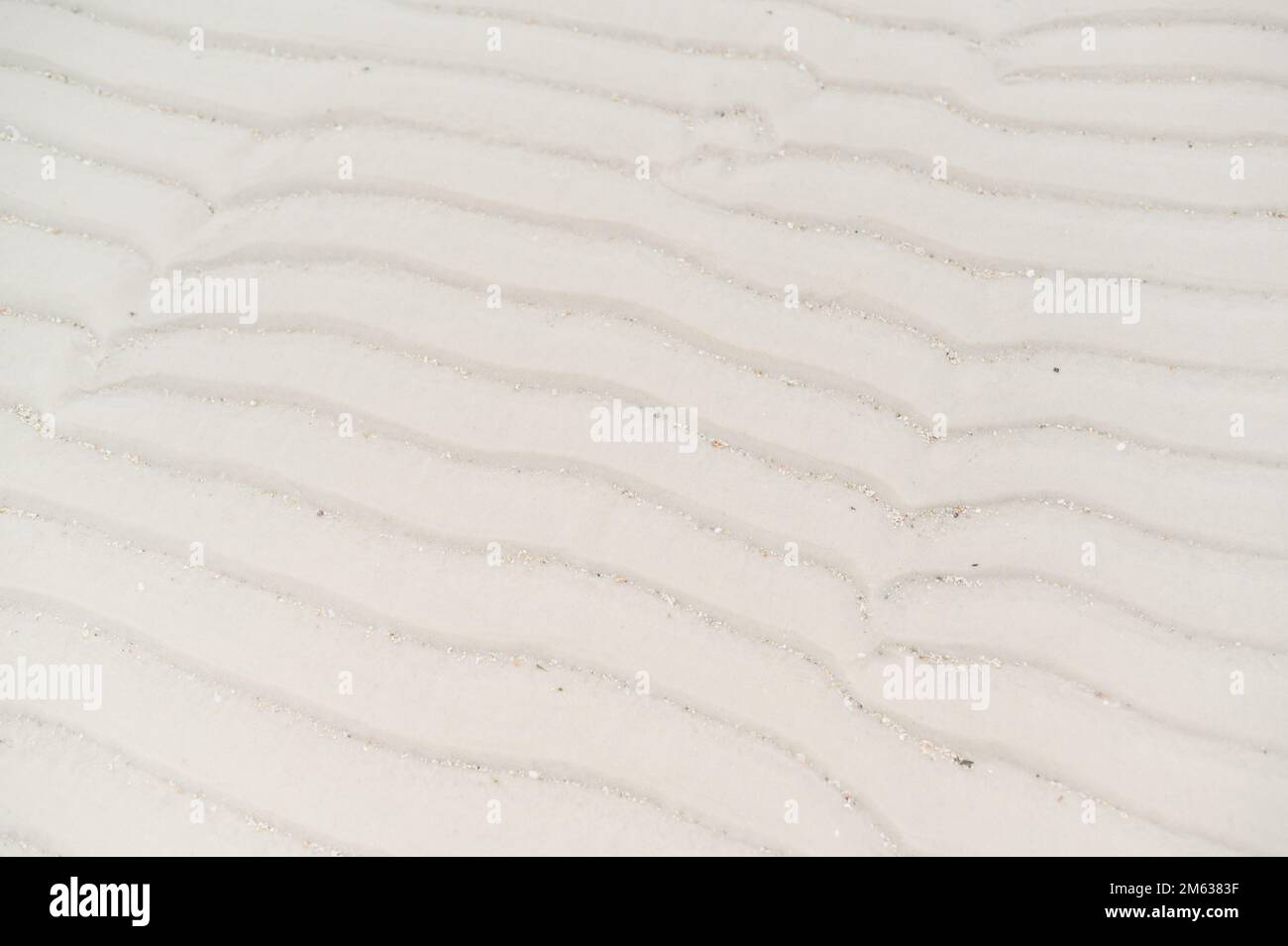 From above of textured background of white rippled beach and sand ...