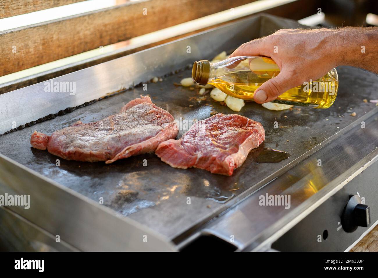 High angle of crop anonymous male chef pouring oil on raw meat pieces ...