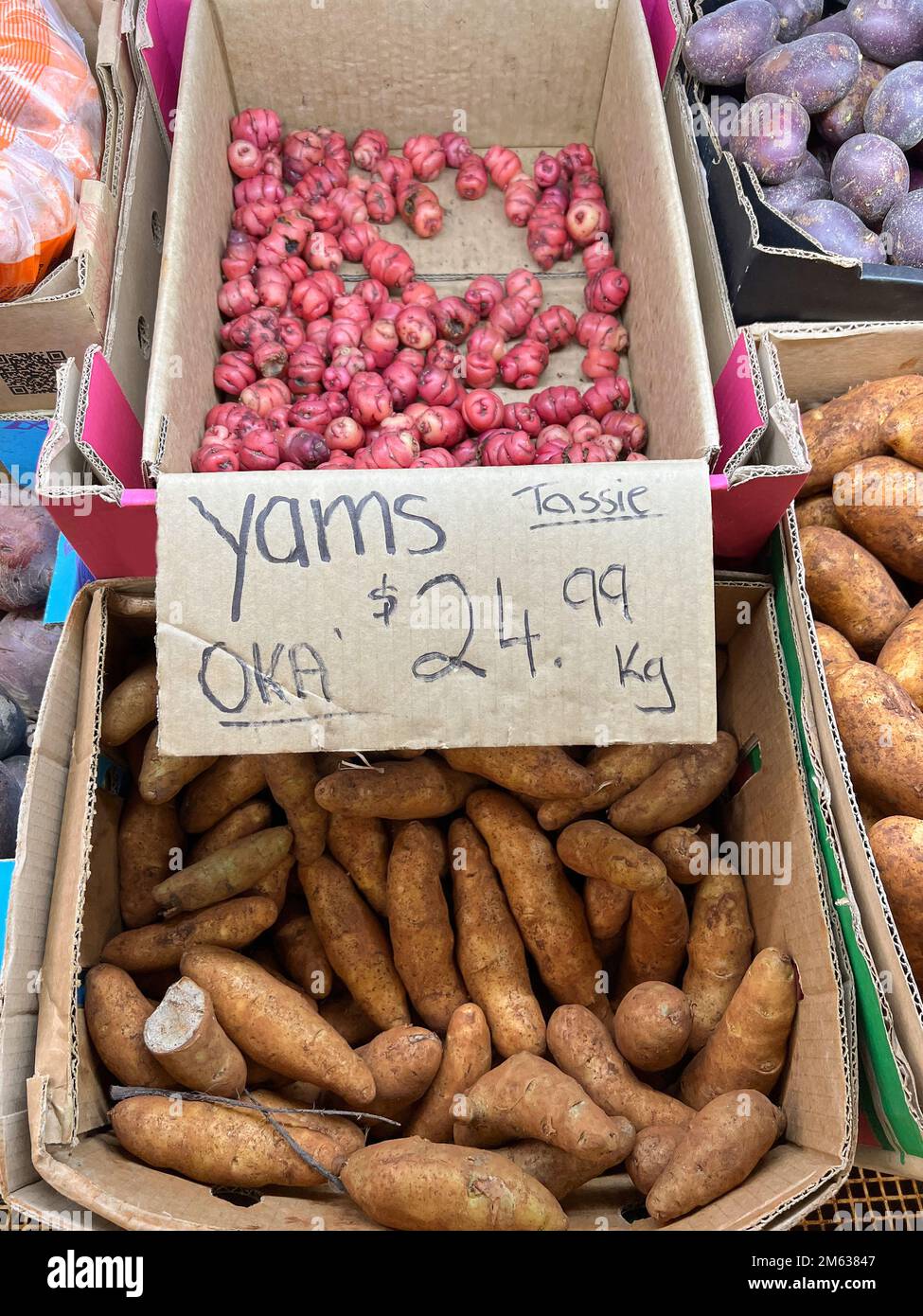 From above of raw sweet potatoes and fresh red oca in carton box placed ...