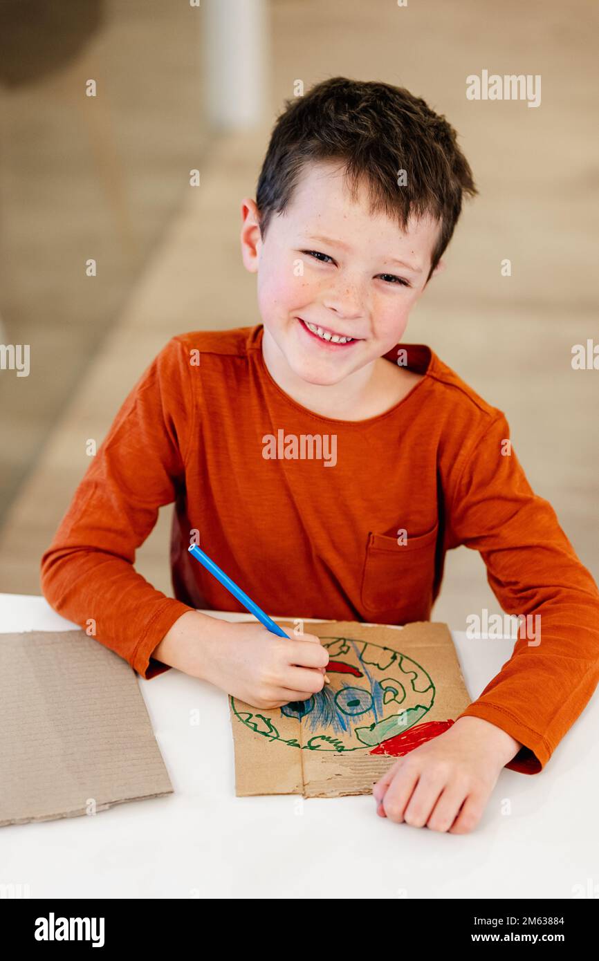 From above positive boy in casual clothes looking at camera with smile ...