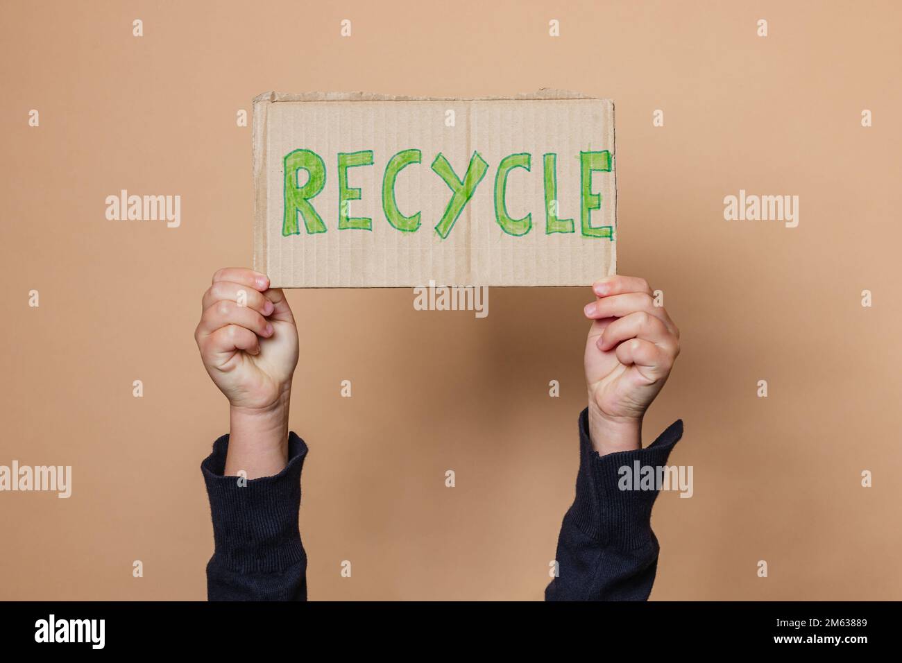 Unrecognizable kid raising arms with carton Recycle placard during ...