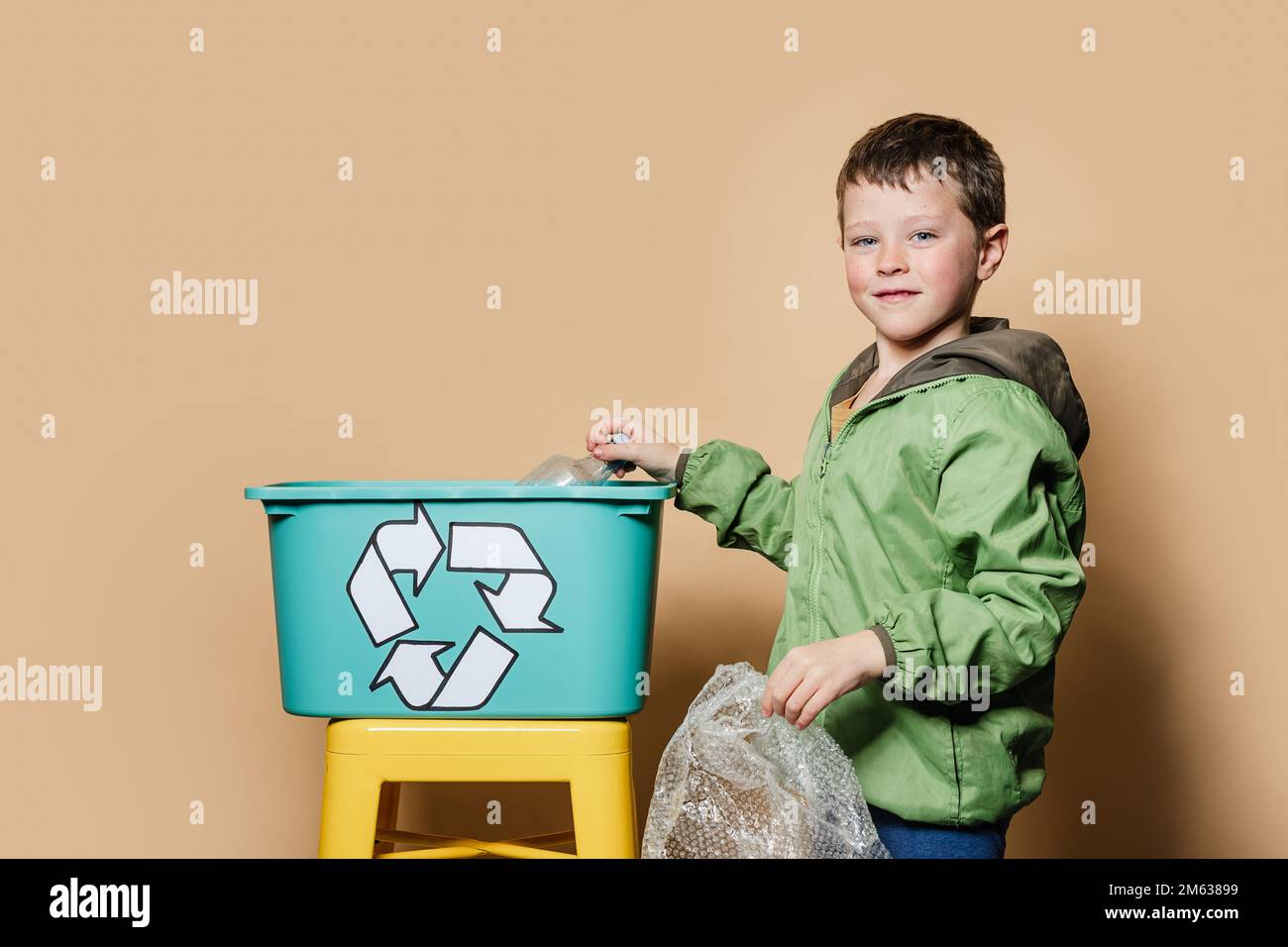 Cute boy in green coat looking at camera with smile and putting ...