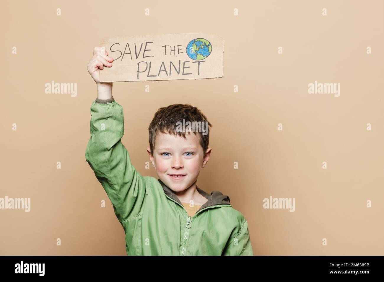 Boy demonstrating carton placard with Save the Planet inscription and ...