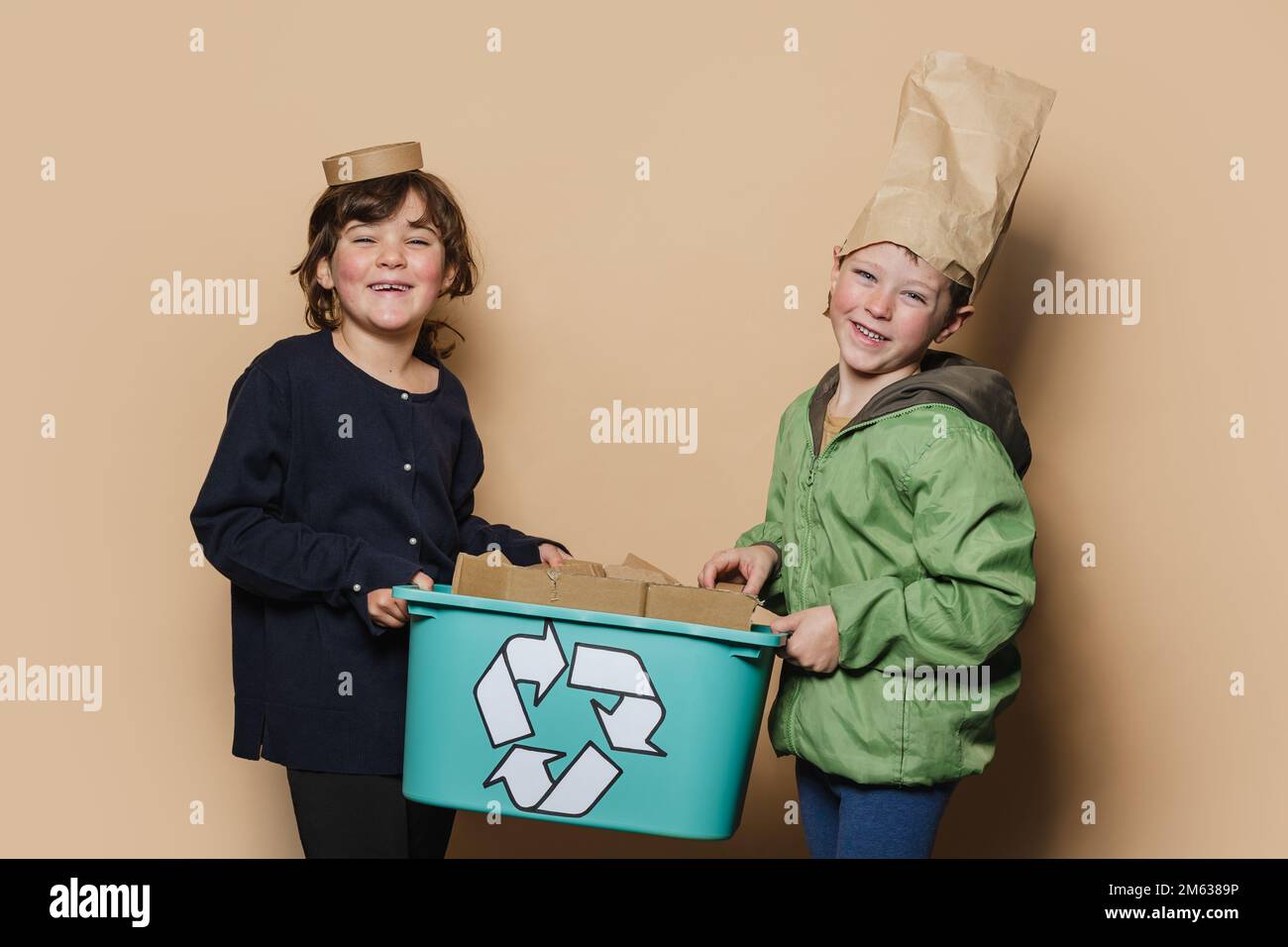 Happy siblings in casual clothes with paper litter on head carrying ...