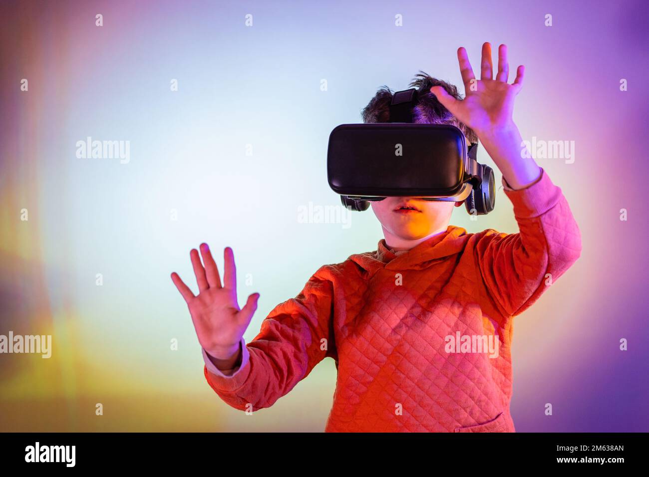 Child in VR goggles interacting with virtual world touching invisible ...