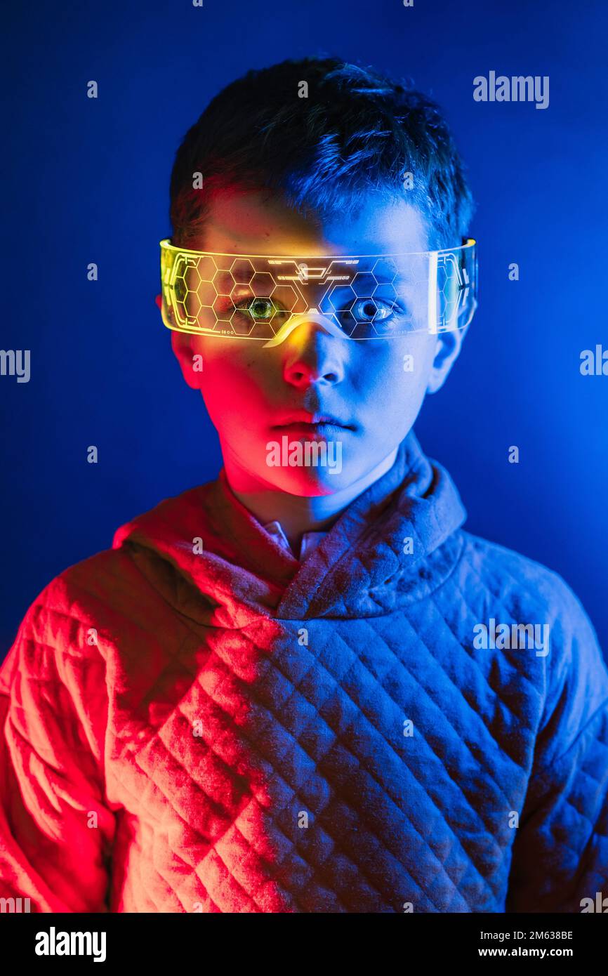 Kid in smart goggles with widely opened eyes exploring virtual space ...