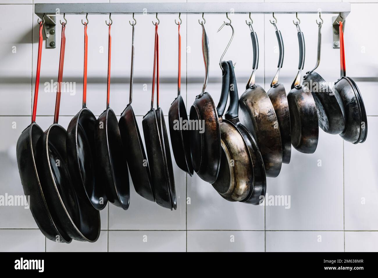 Various sized metal pans hanging in row on hooks attached to railing ...