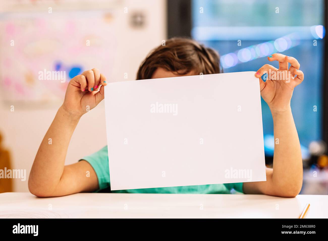 Unrecognizable girl demonstrating empty paper sheet while sitting at ...