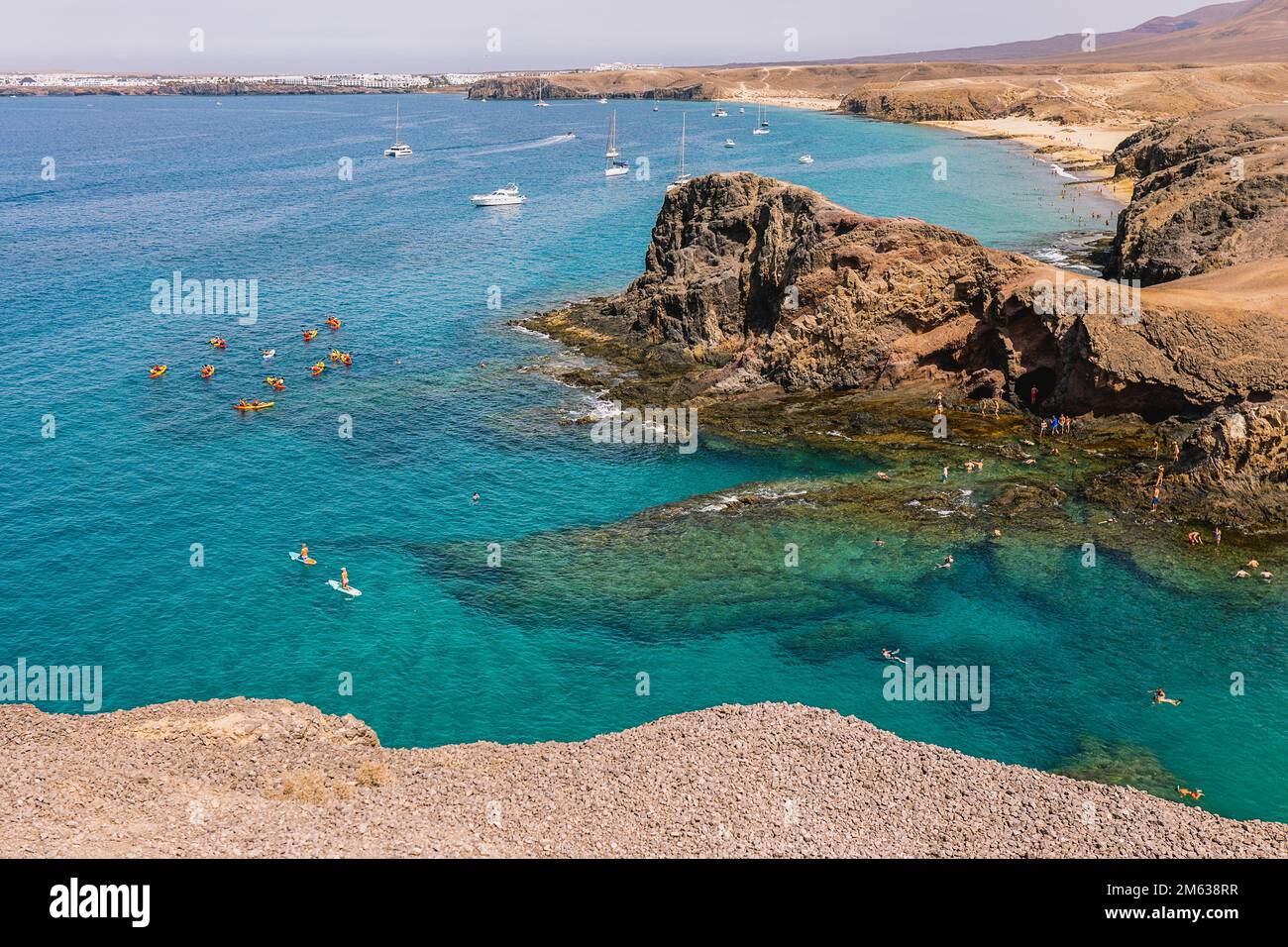 Aerial view of blue sea water with lots of people on cliffside parrot ...