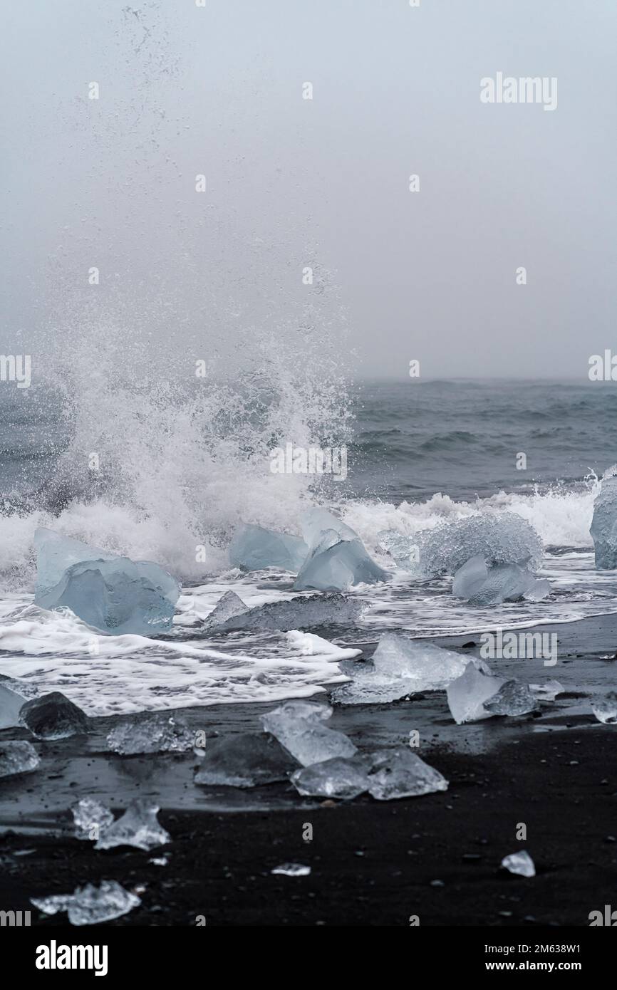 Frozen pieces of ice in cold water with splashing wave under gray sky ...