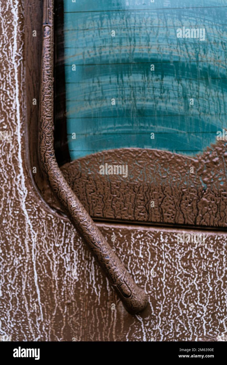Muddy rear car window with wiper covered by water drops on rainy day ...