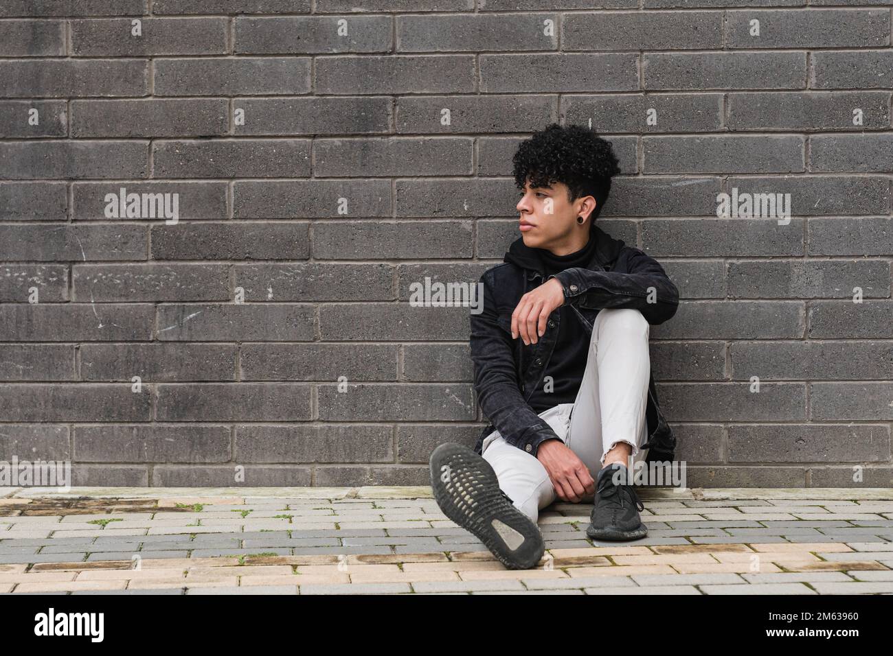 Full body of young ethnic male migrant in casual outfit sitting on ...