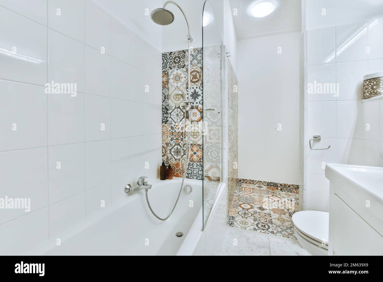White ceramic tub placed near shower at mosaic wall in light spacious ...