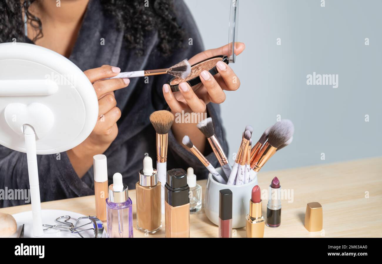 Crop unrecognizable female in black bathrobe sitting near wooden table ...