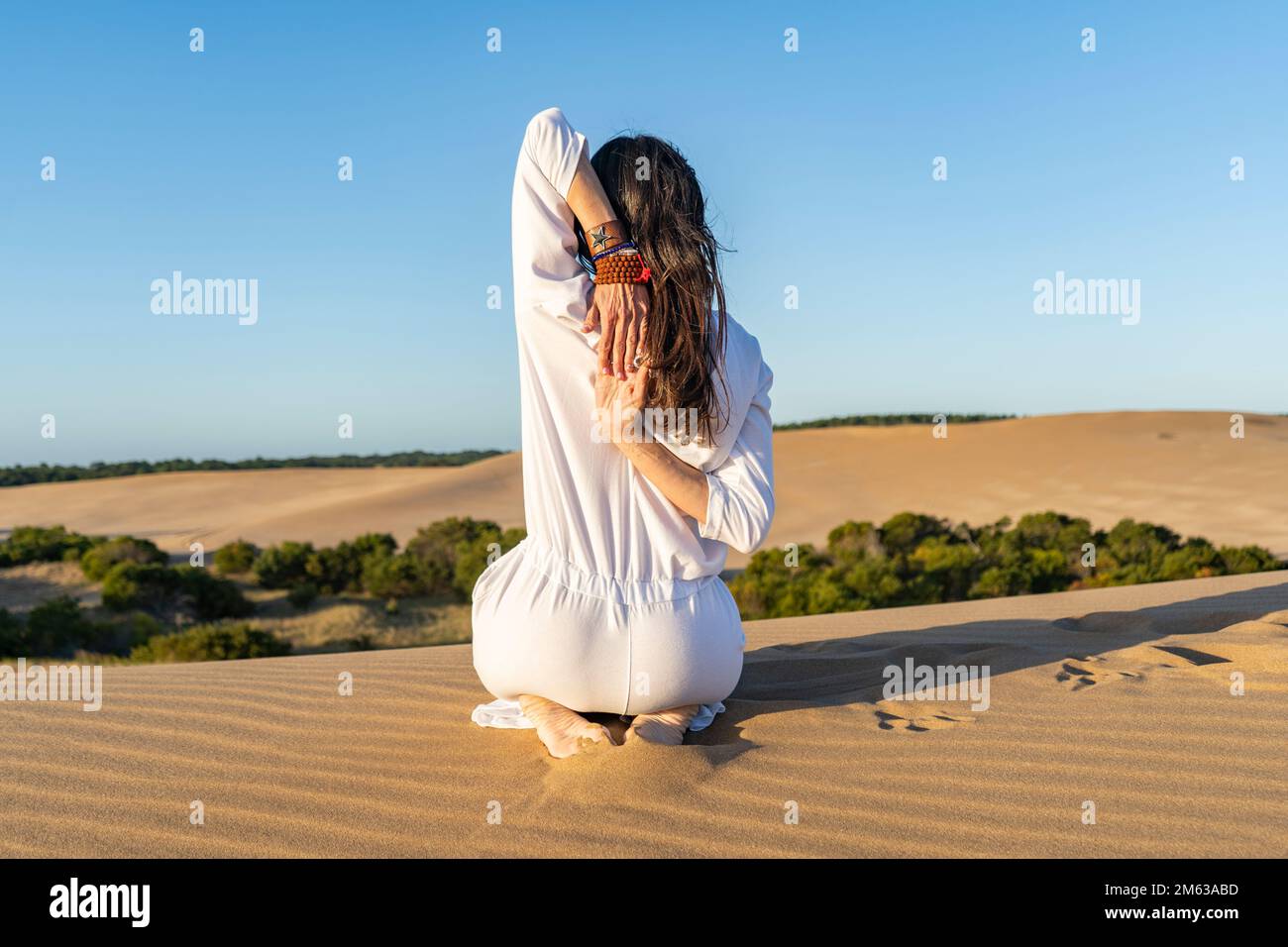 Back view of unrecognizable lady performing Cow Face pose while sitting ...