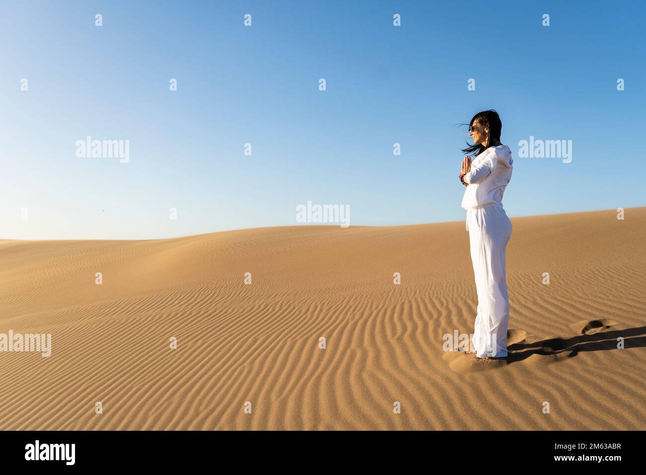 Full length side view of calm female standing on sand in desert of Argentina and demonstrating ...