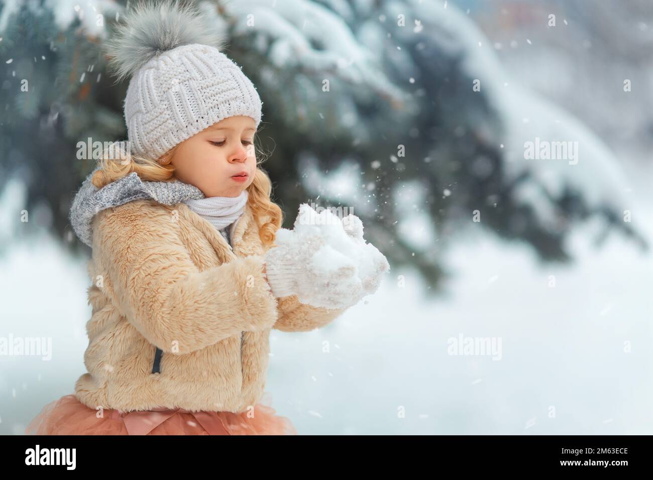 A girl in winter blowing snow off her hands in a snowy forest Stock ...