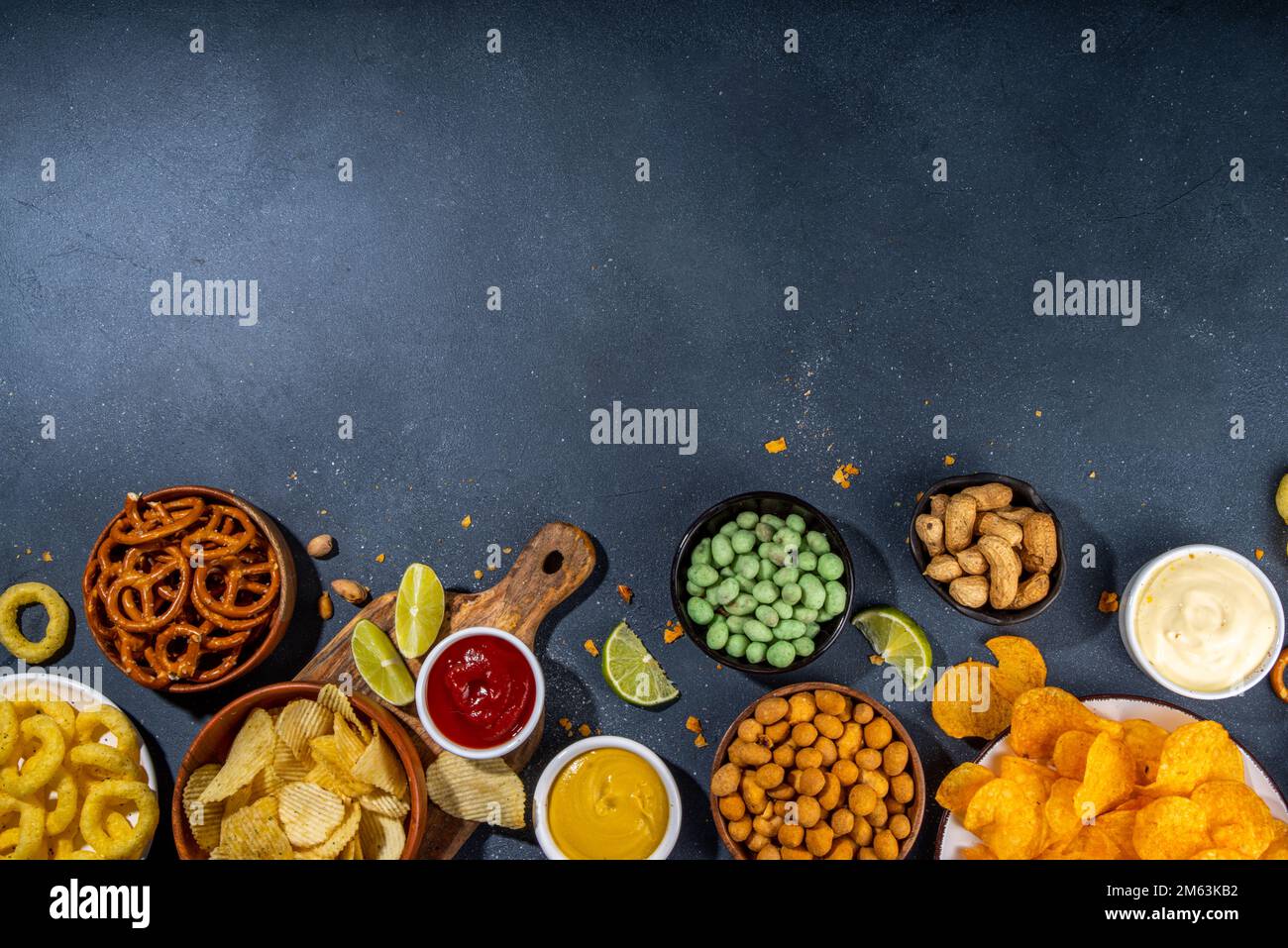 Various unhealthy salty bar snacks set. Dark grey table background with ...
