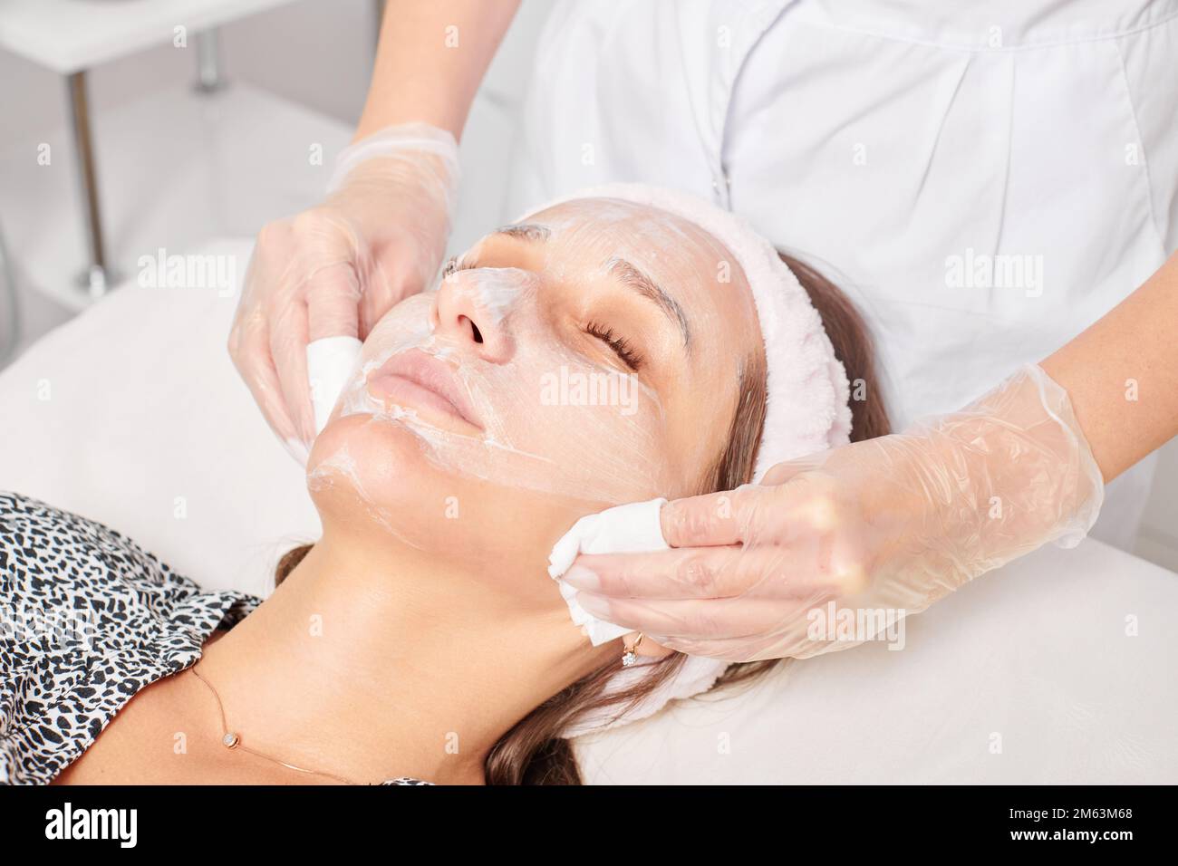 Beautician removing facial cream mask from woman face skin with ...