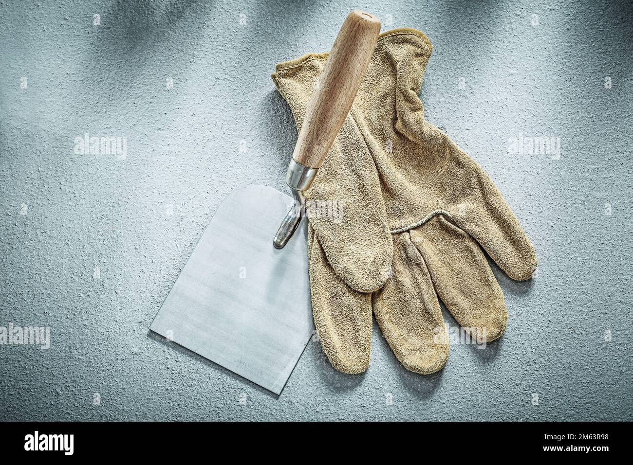 Stainless putty knife leather protective glove on concrete background ...