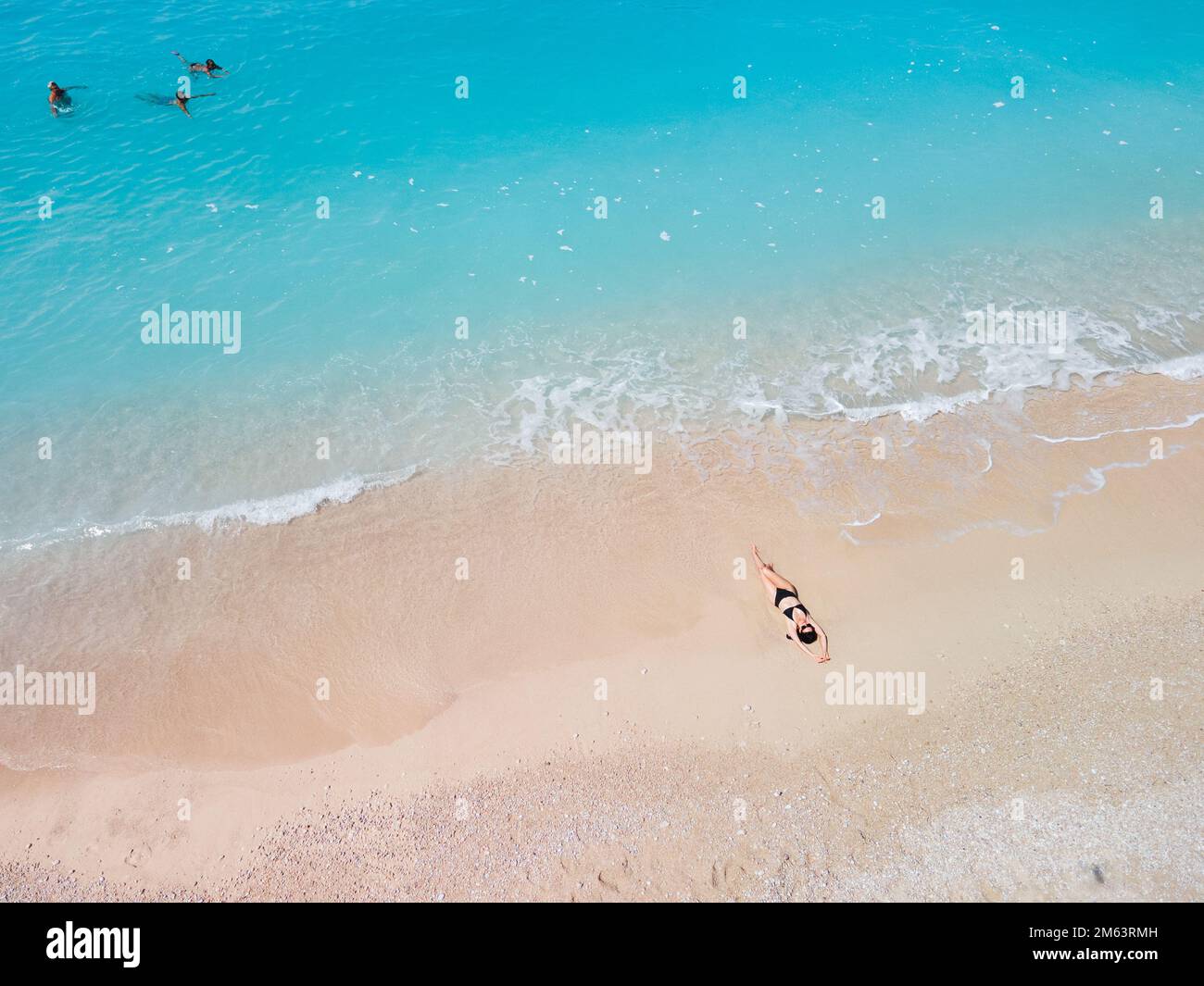 overhead view of woman in black swimsuit sunbathing at sea shore Stock ...