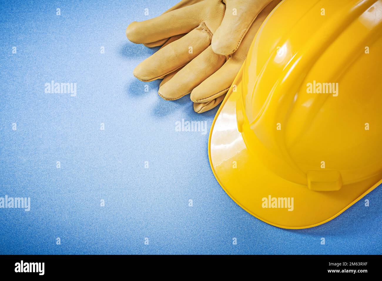 Yellow building helmet leather protective gloves on blue background ...