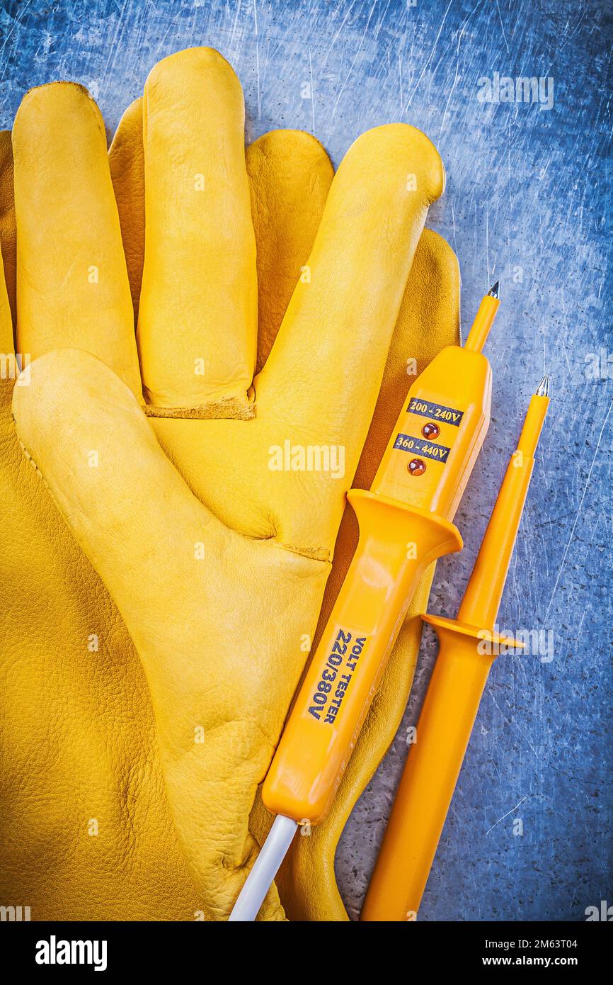 Yellow electrical tester protective gloves on metallic background ...