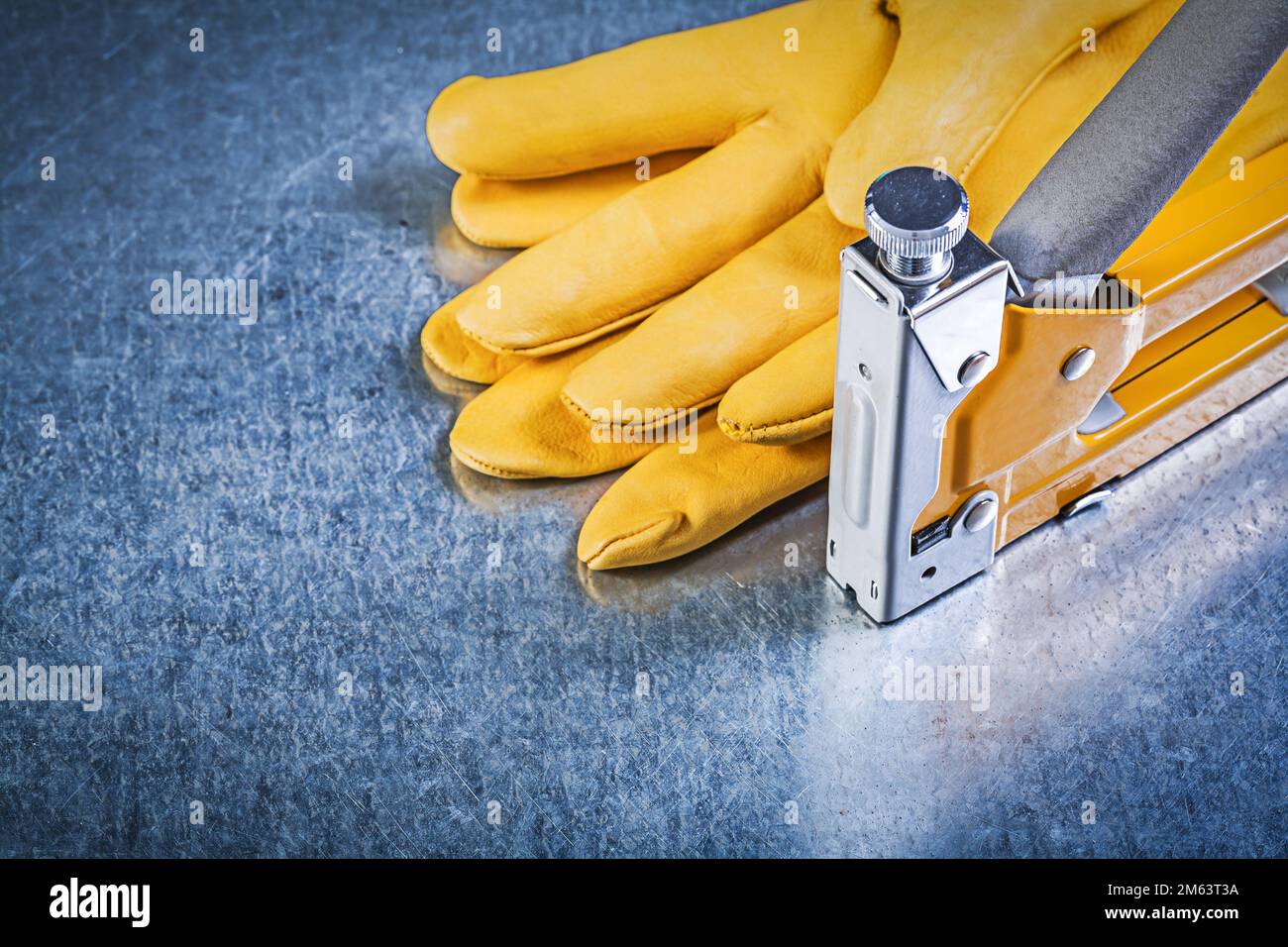 Yellow leather protective gloves construction stapler on metallic ...