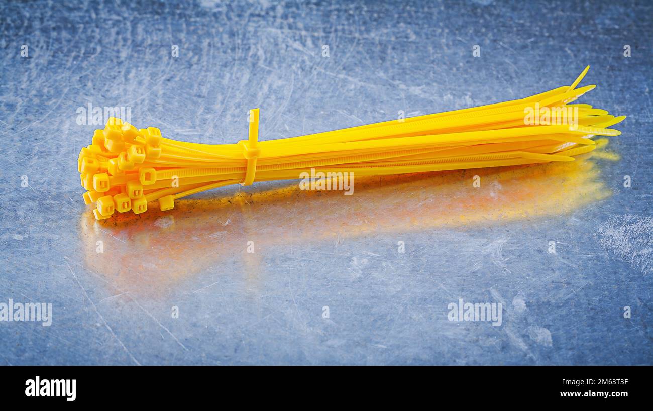 Yellow plastic self-locking cable ties on metallic background ...