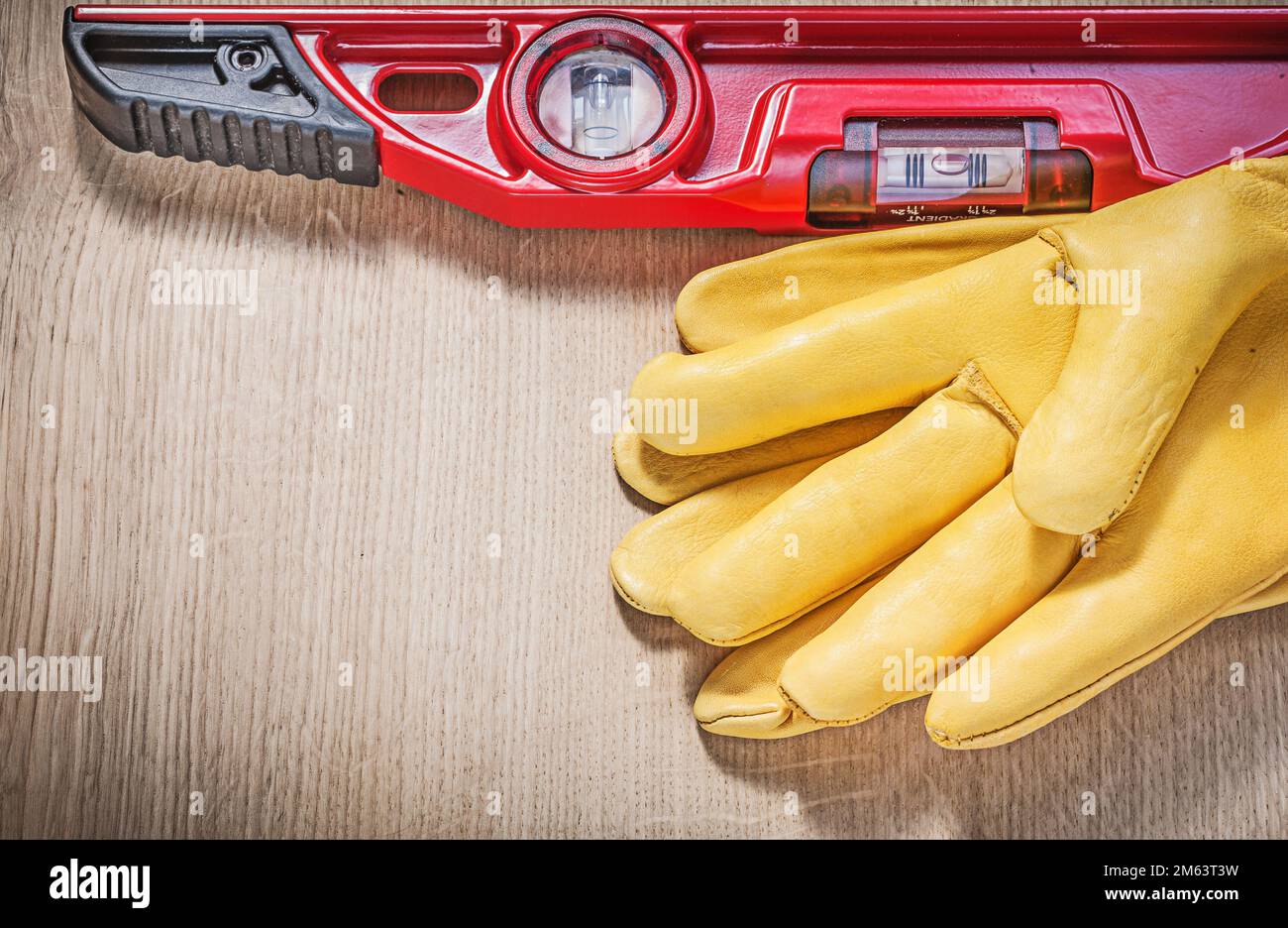 yellow gloves and red construction level on wood board Stock Photo - Alamy