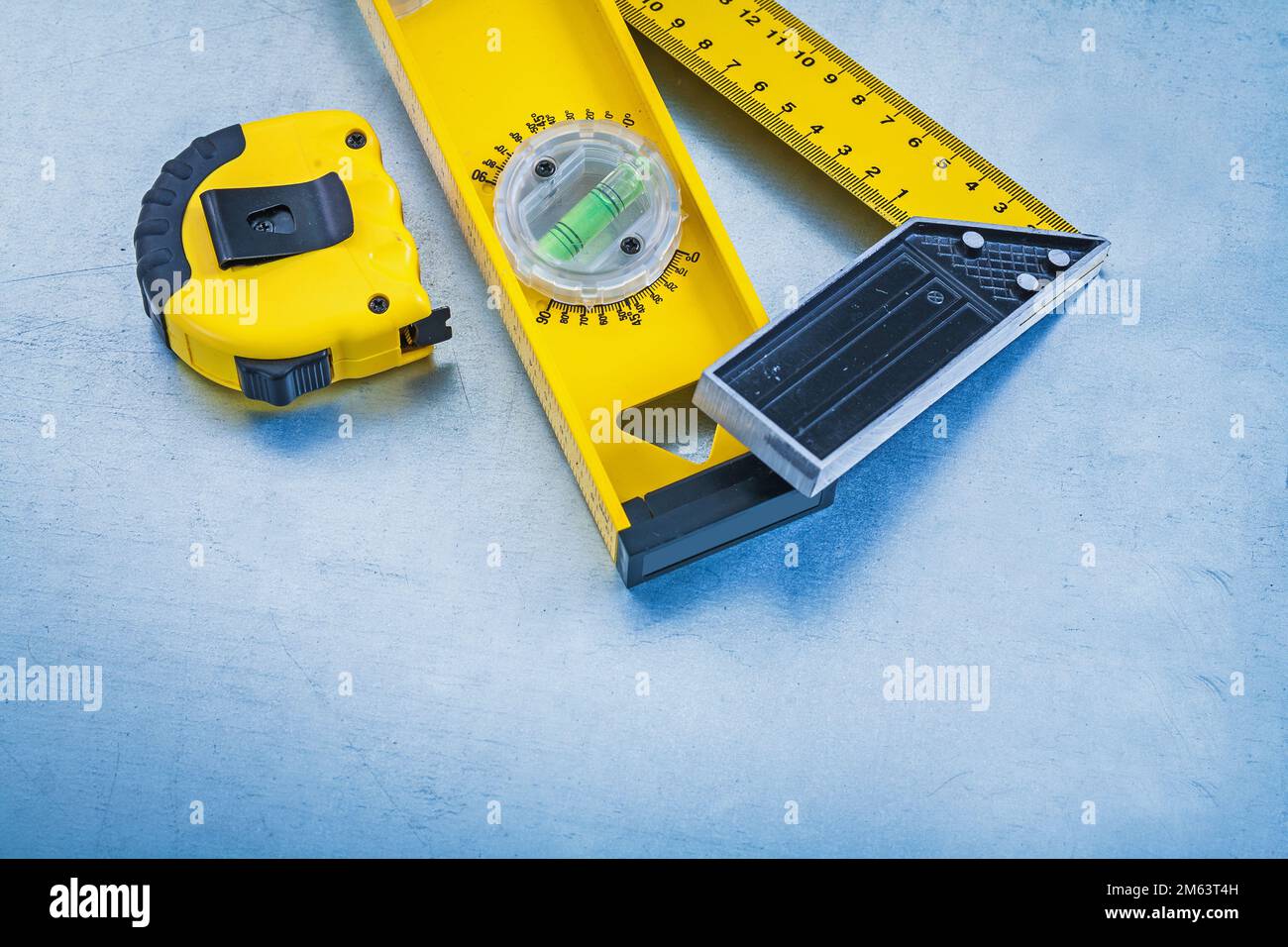 Yellow measuring tape construction level and square ruler on metallic ...