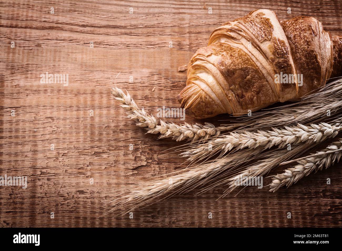 Yummy croissant bunch of wheat ears on oak wooden board food and drink ...